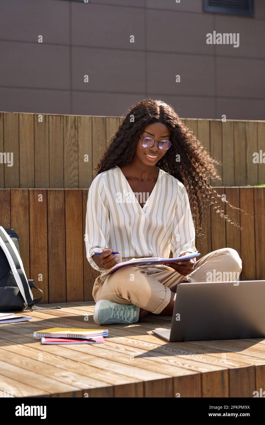 Happy African girl student elearning using laptop studying outside ...