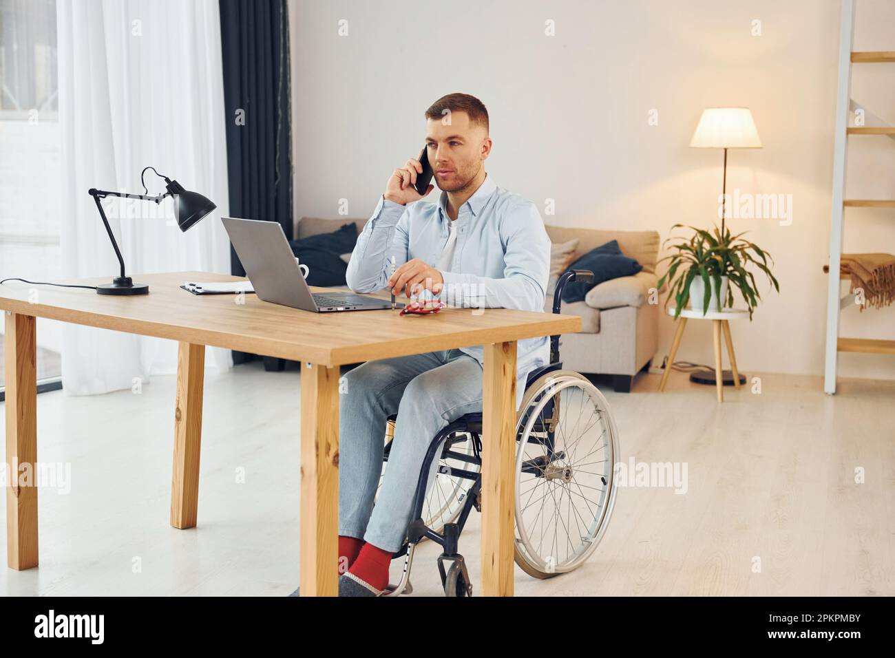 Using laptop. Disabled man in wheelchair is at home Stock Photo - Alamy