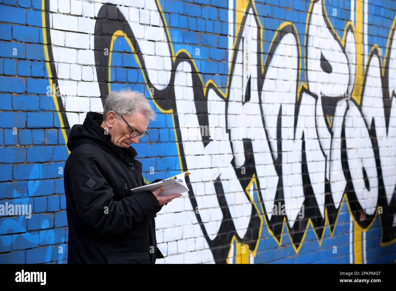 A fan reads the official match day programme ahead of the Premier ...