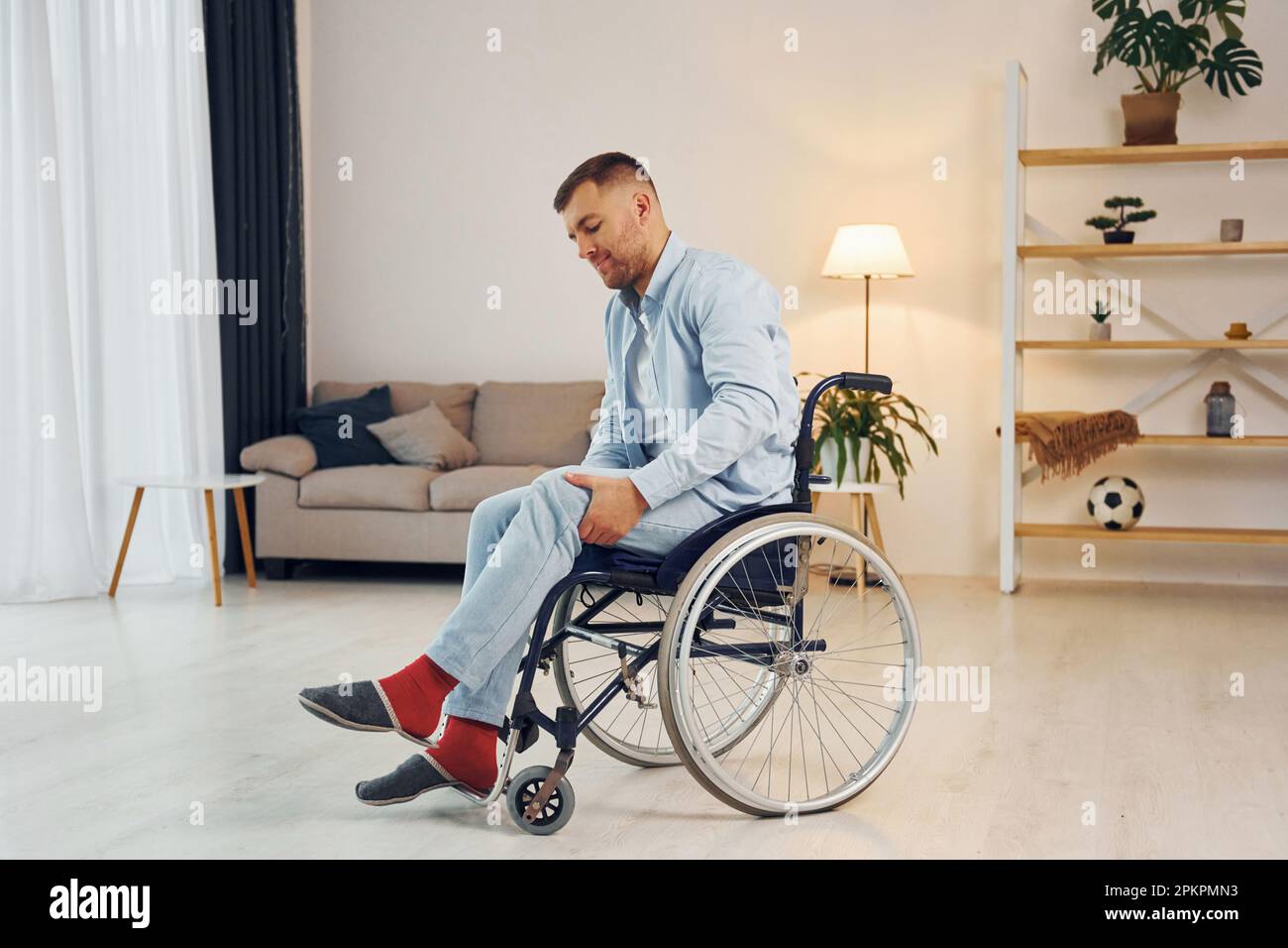 Trying to move. Disabled man in wheelchair is at home Stock Photo - Alamy