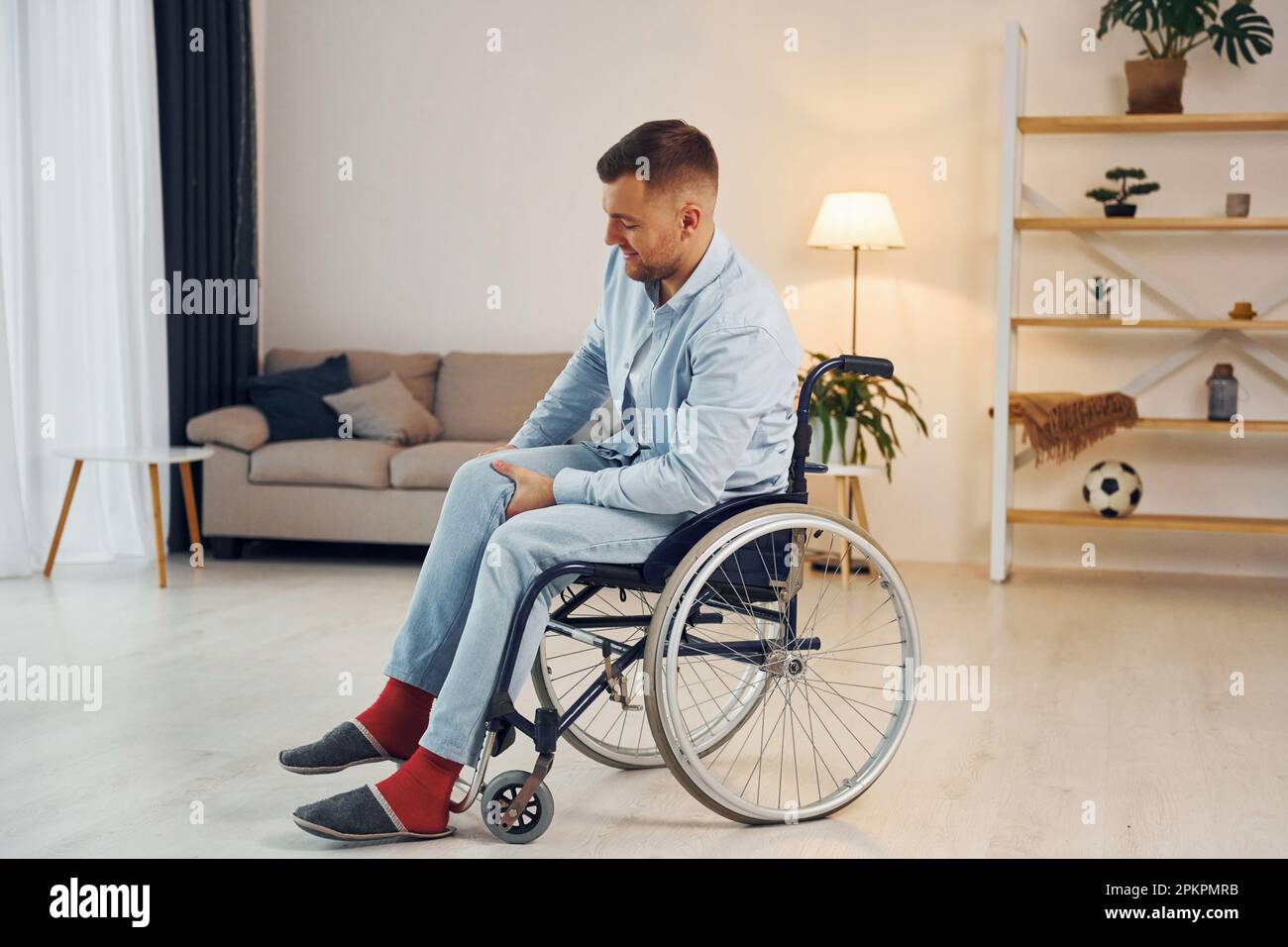 Trying to move. Disabled man in wheelchair is at home Stock Photo - Alamy