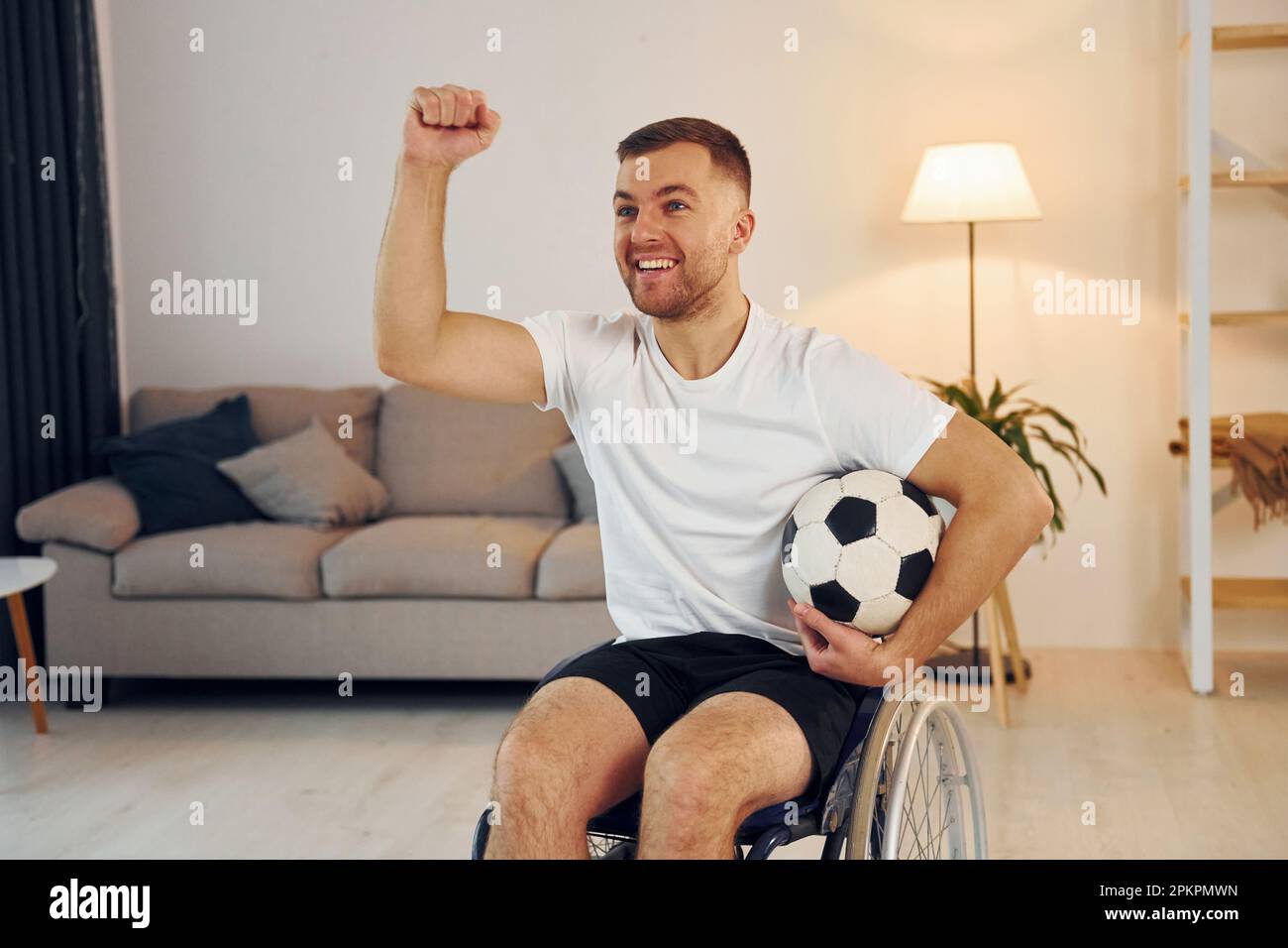 With soccer ball. Disabled man in wheelchair is at home Stock Photo - Alamy