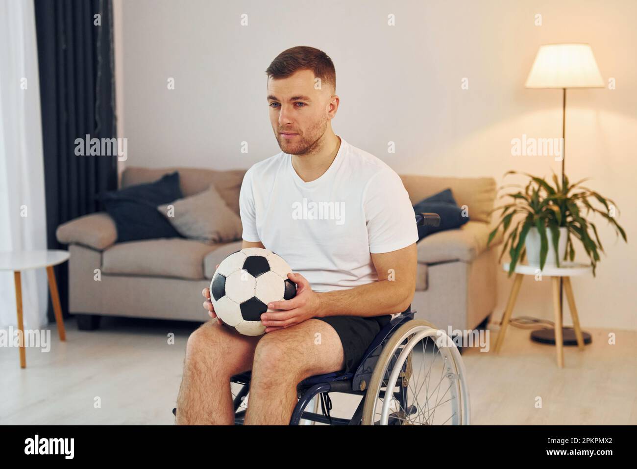 With soccer ball. Disabled man in wheelchair is at home Stock Photo - Alamy