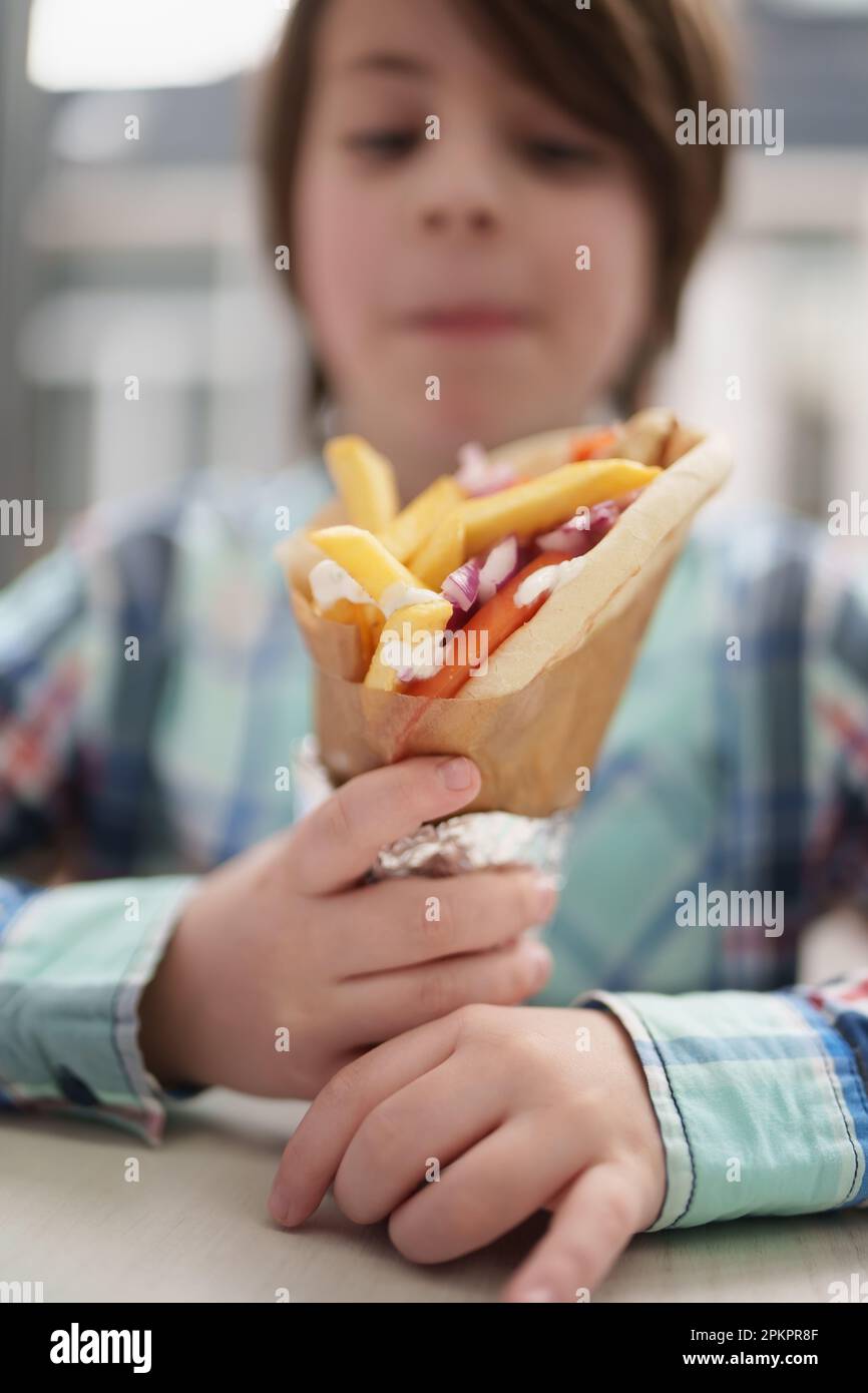 Hungry little boy holding gyros sandwich wrapped in pita bread. White ...