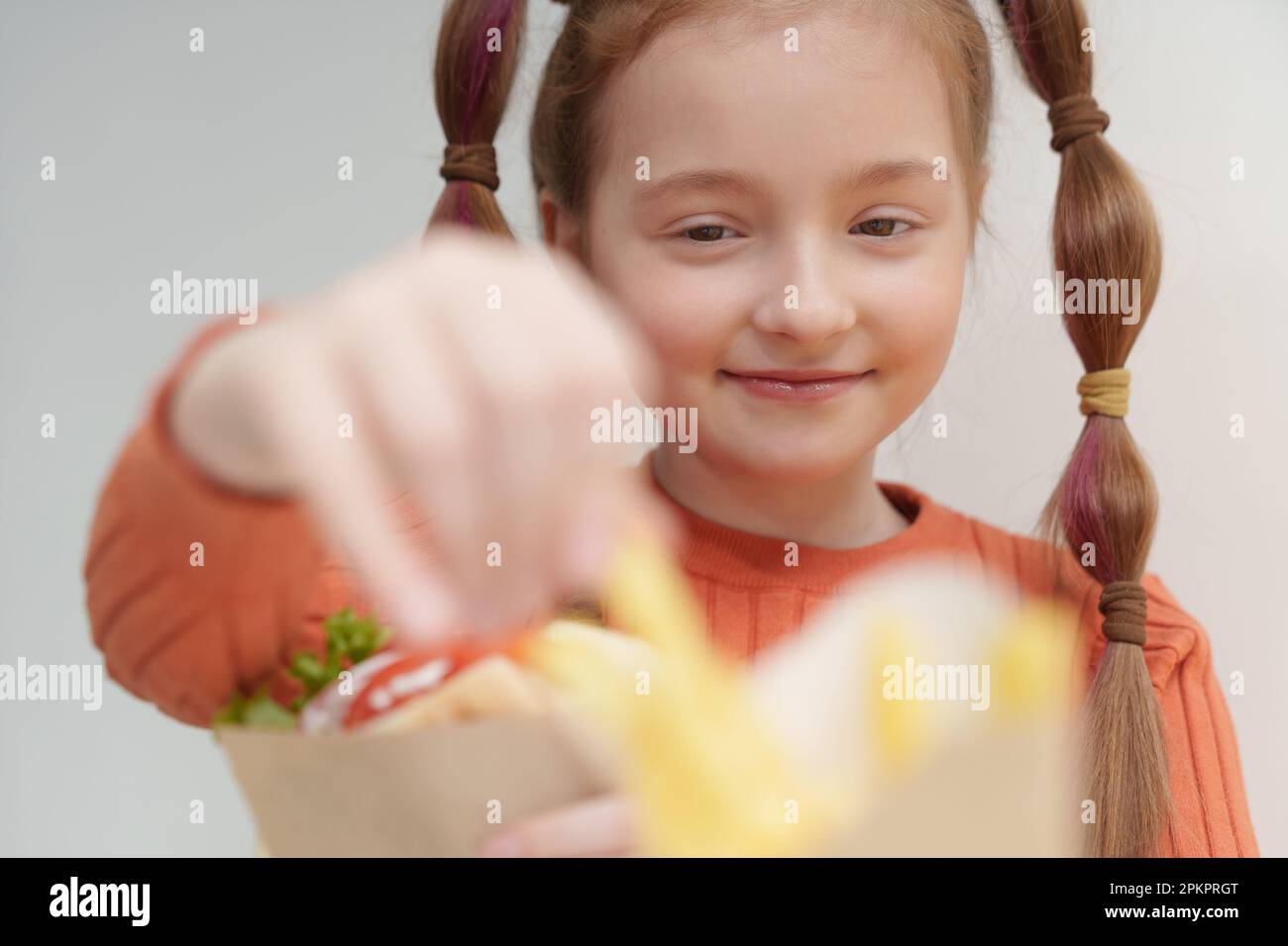 Cute little girl eating fries in a fast food restaurant. Portrait of ...