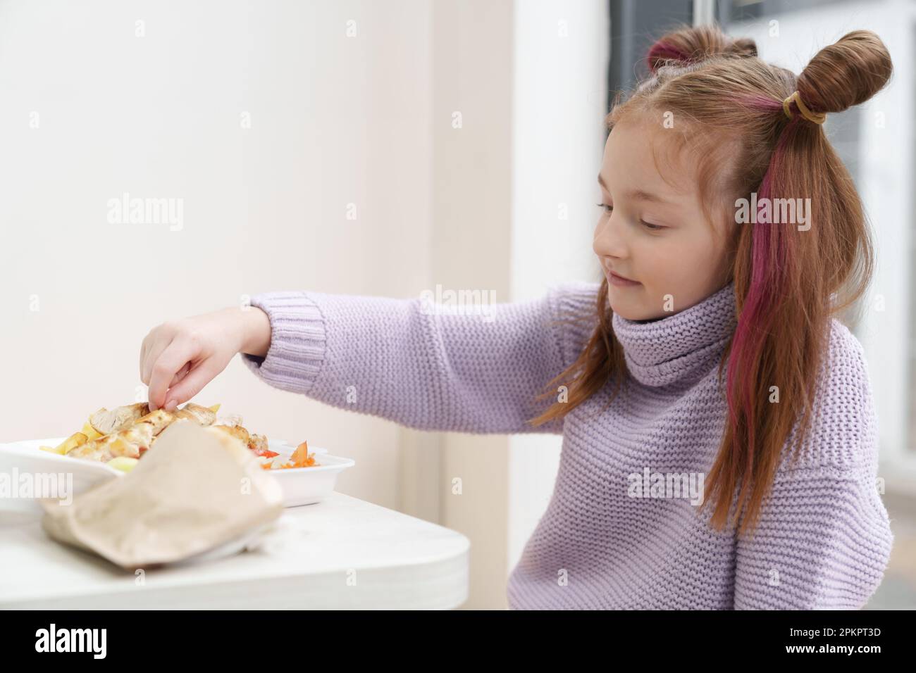 Hungry little girl eating traditional Greek kalamaki dish from a lunch ...