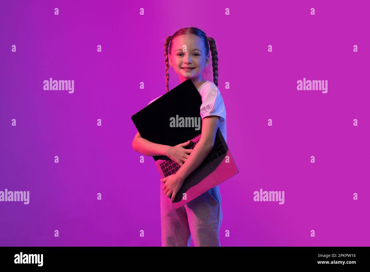 Sweet blondy preteen girl hugging open lapotp with blank screen Stock ...