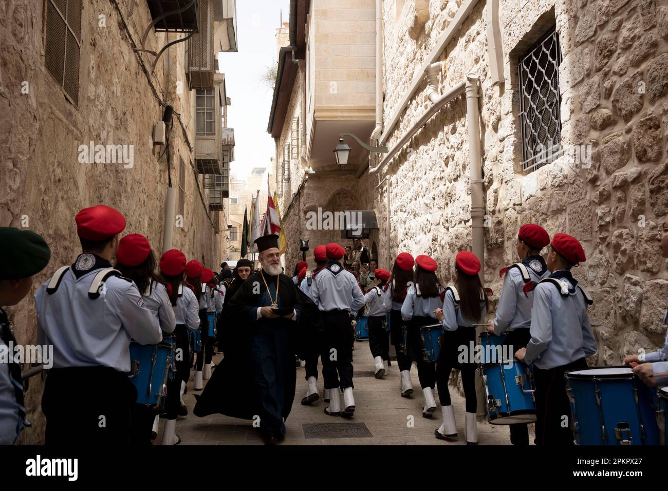 A Greek Orthodox clergy member passes through a scout band procession ...