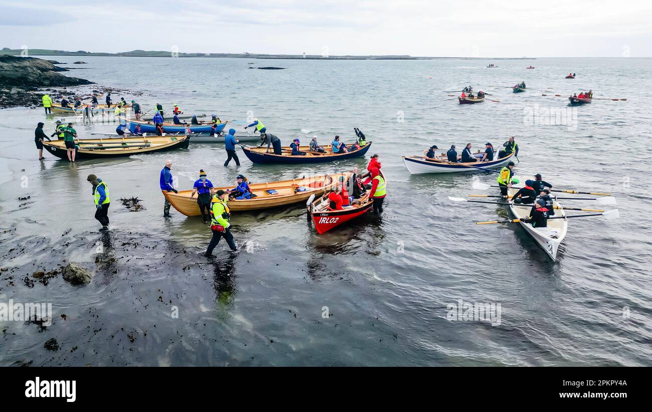 Rowers on traditional wooden skiff rowing boats land their boats on a ...