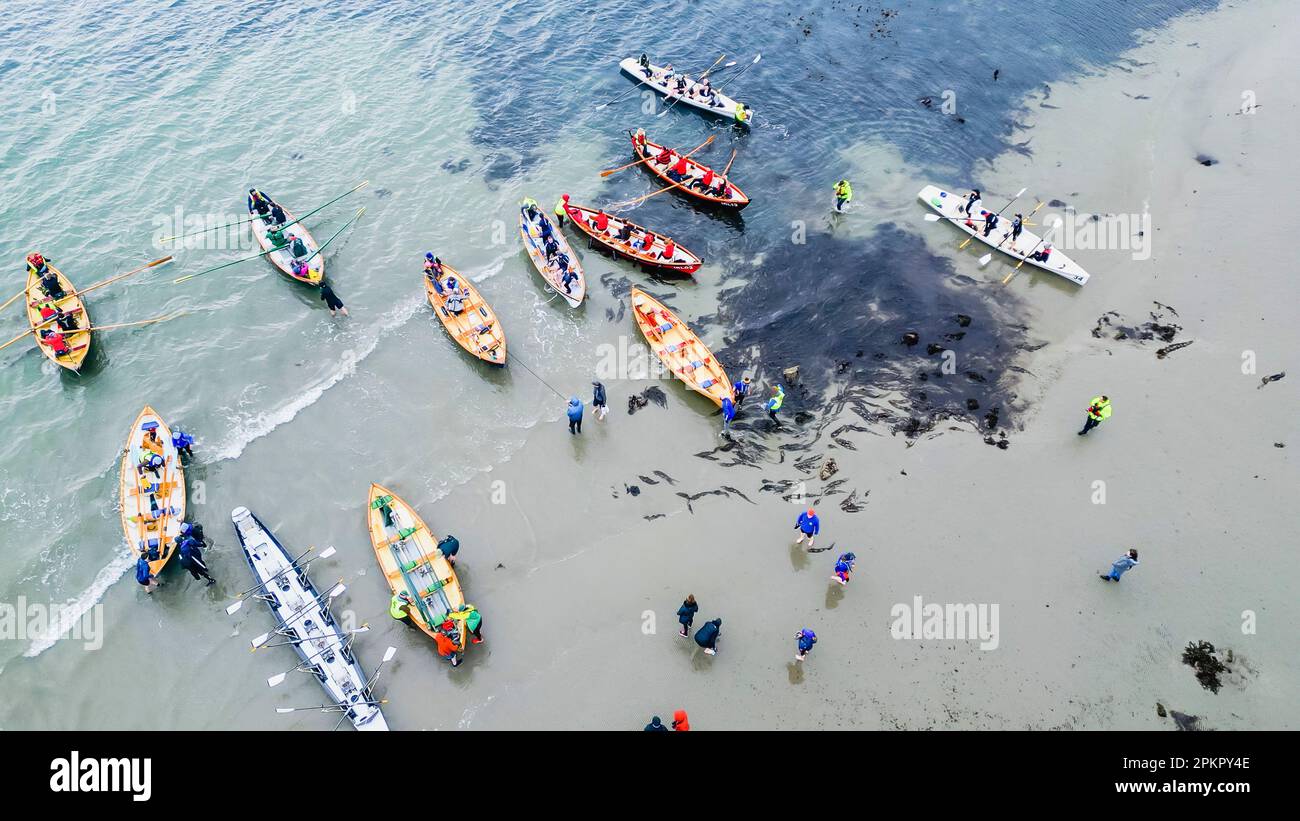 Rowers on traditional wooden skiff rowing boats land their boats on a ...