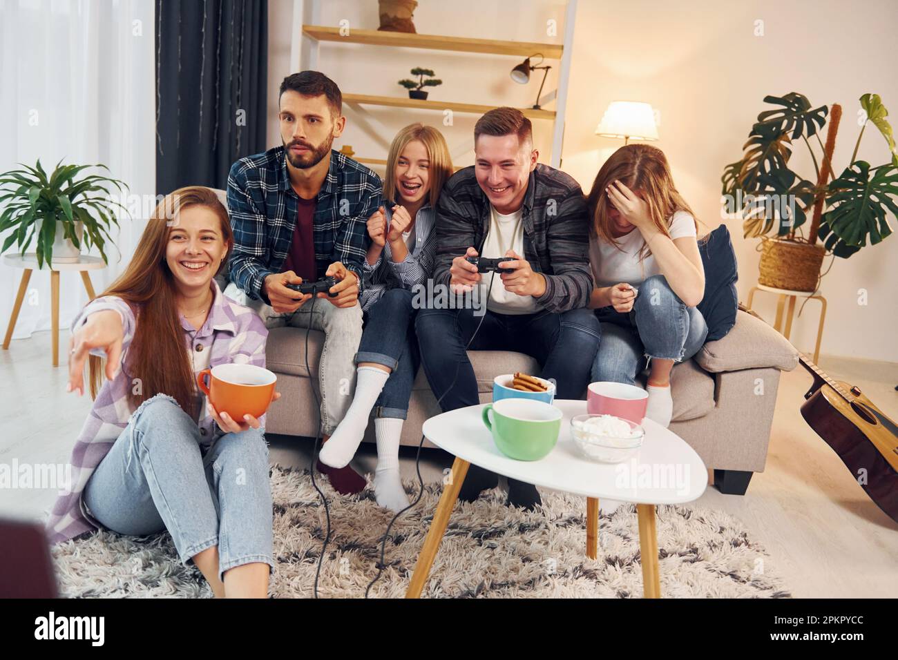 Free time entertainment. Group of friends have party indoors together ...