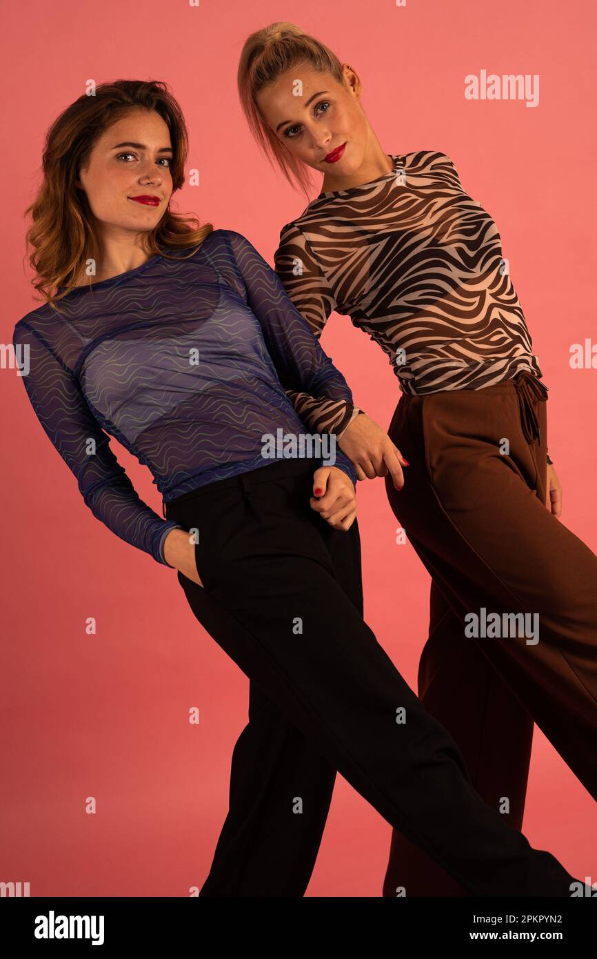 Two beautiful girls stand together on a red background Stock Photo - Alamy
