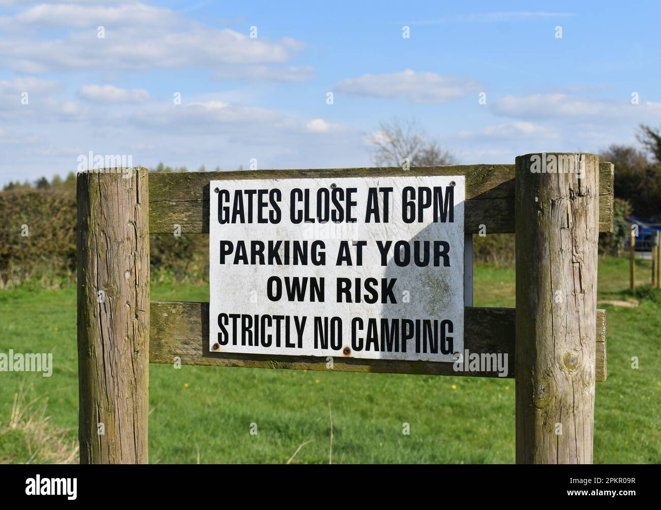 A sign in a field: "Gates close at 6pm. Parking at your own risk ...
