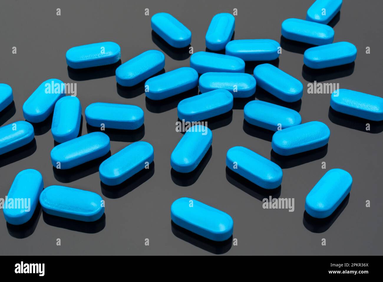Blue pills on reflective dark background. For medicine, illness and ...