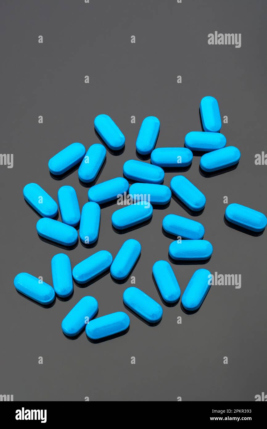 Blue pills on reflective dark background. For medicine, illness and ...