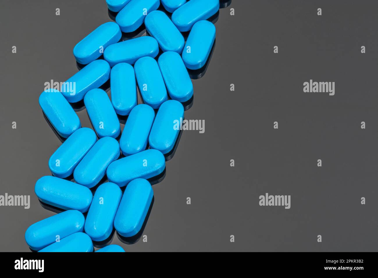 Blue pills on reflective dark background. For medicine, illness and ...