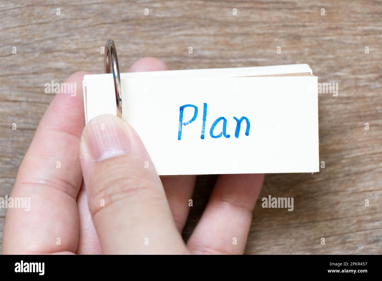 Hand hold flash card with handwriting in word plan on wood background ...
