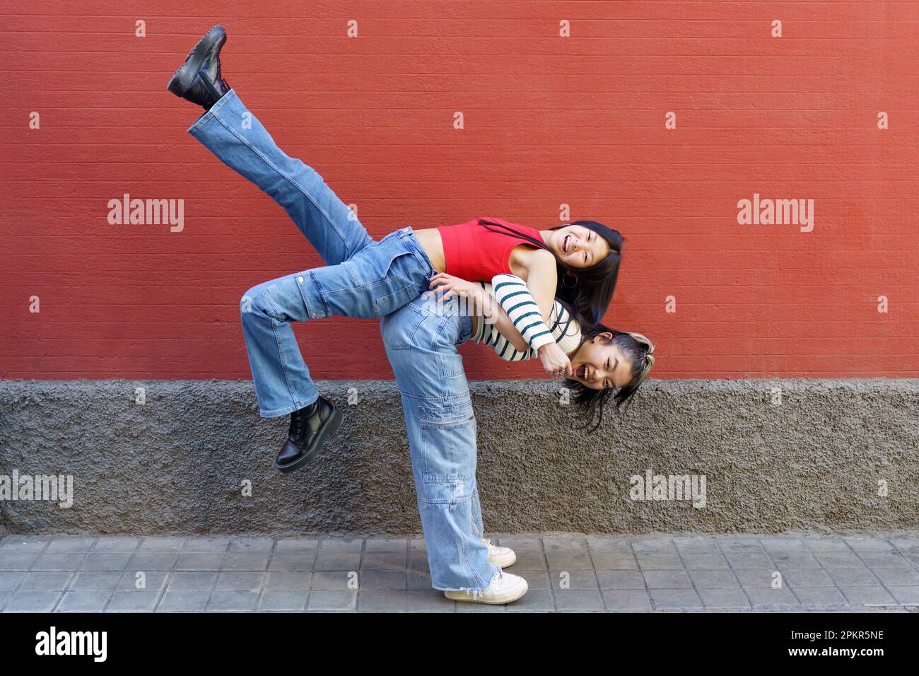 Happy Asian female lifting friend on back Stock Photo - Alamy