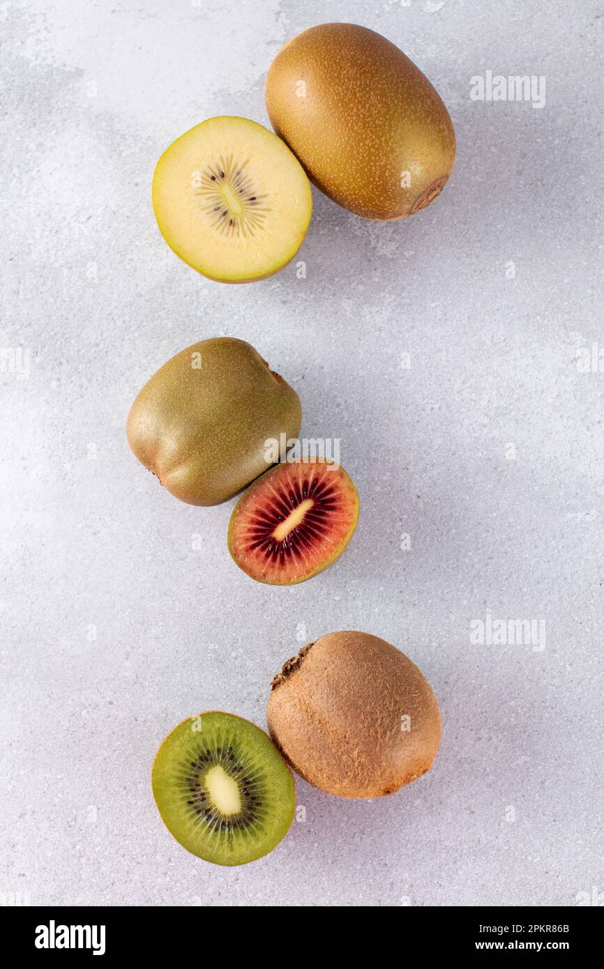 Different varieties of kiwi lie in a pile on the table. Halves of red ... Different varieties of kiwi lie in a pile on the table. Halves of red ...