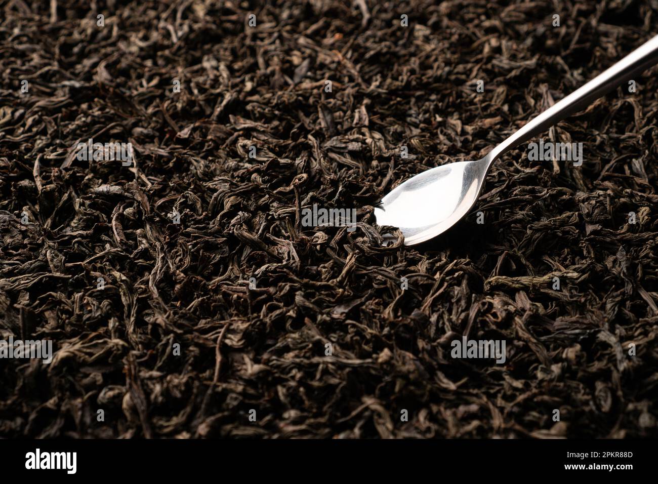A teaspoon scooping up black loose-leaf tea and being examined in ...