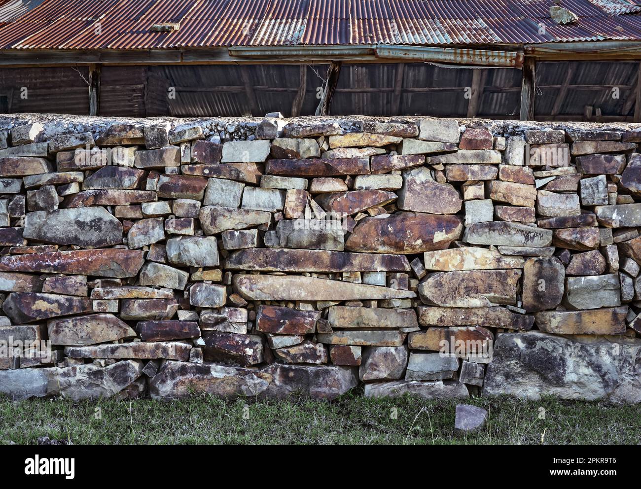 An old handstacked stone wall encloses a cattle 'kraal' (camp) with a ...