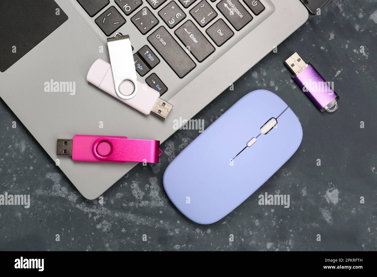 Modern laptop, USB flash drives and blue mouse on grunge background ...