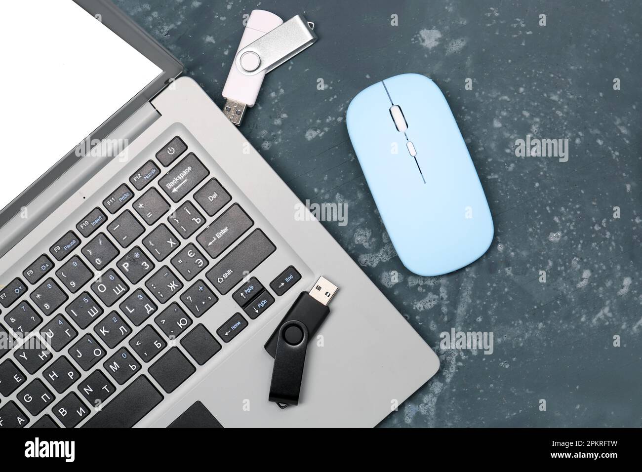 Modern laptop, USB flash drives and blue mouse on grunge background ...