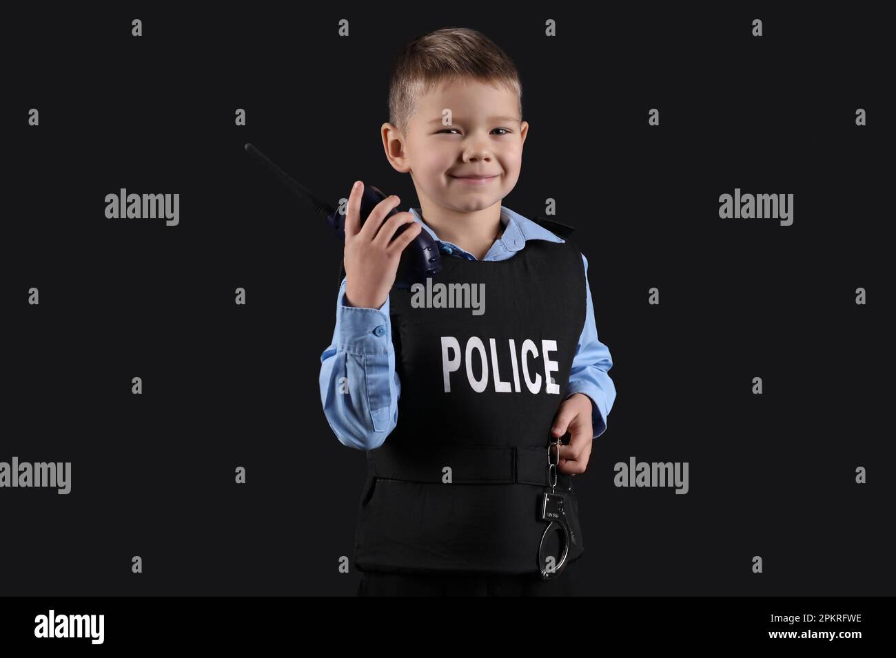 Cute little police officer with radio transmitter on black background ...