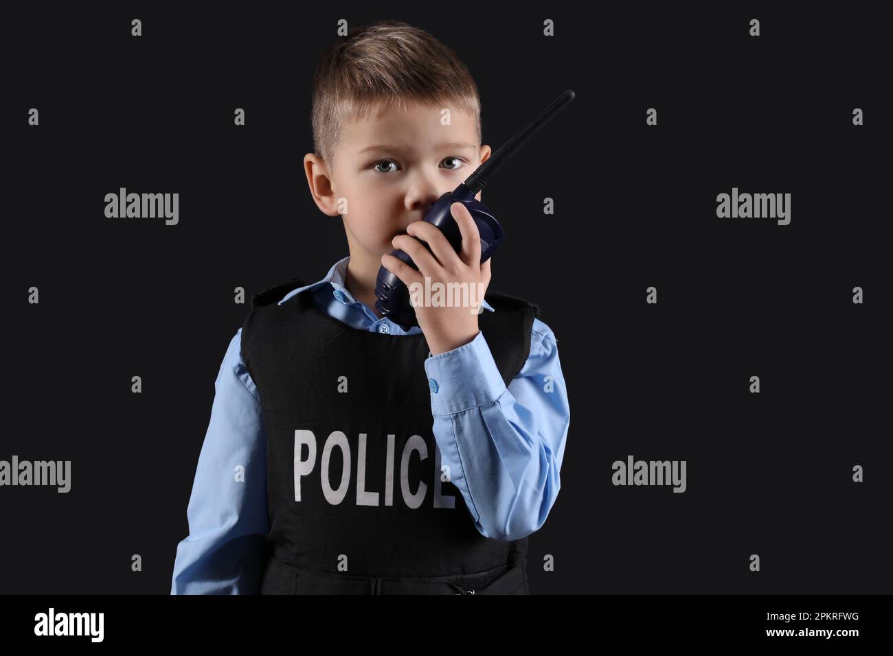 Cute little police officer with radio transmitter on black background ...