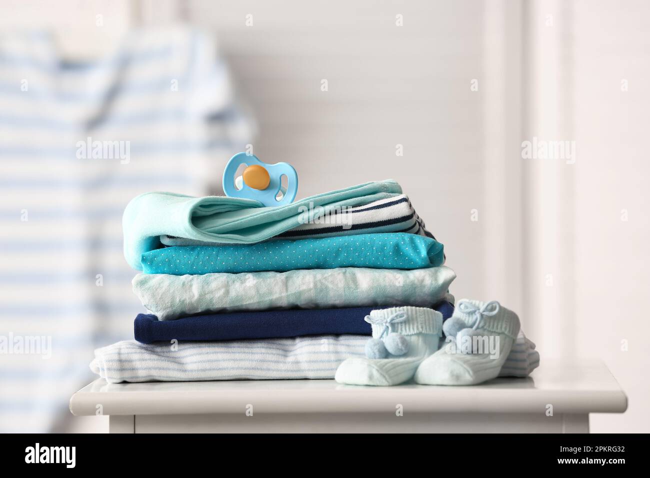 Stack of baby clothes and pacifier on table in room, closeup Stock ...