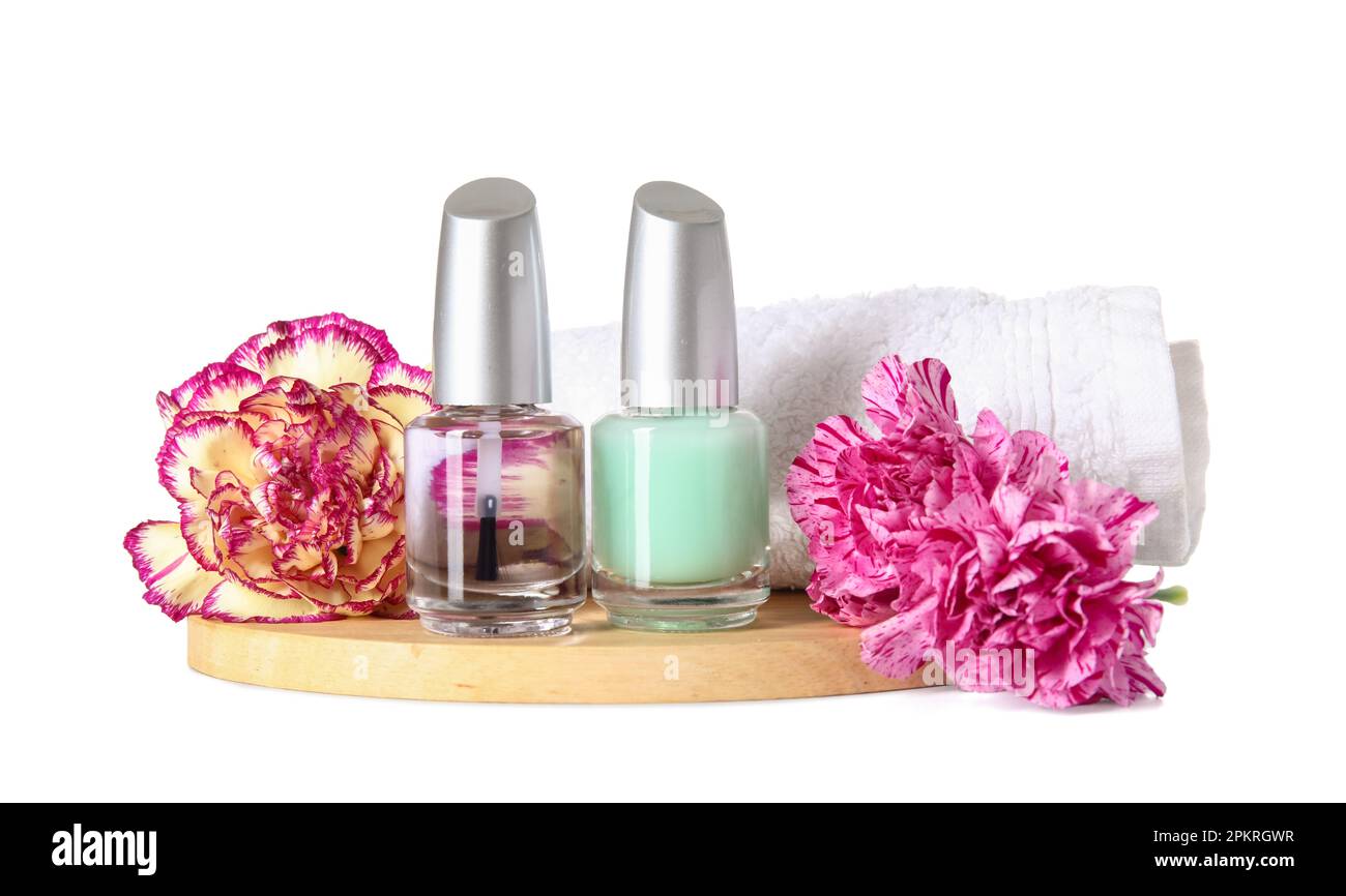 Wooden board with bottles of cuticle oil, towel and carnation flowers ...