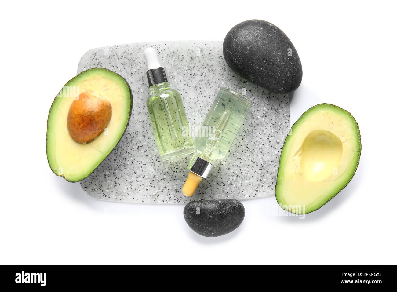 Board with bottles of cuticle oil, avocado and spa stones on white ...