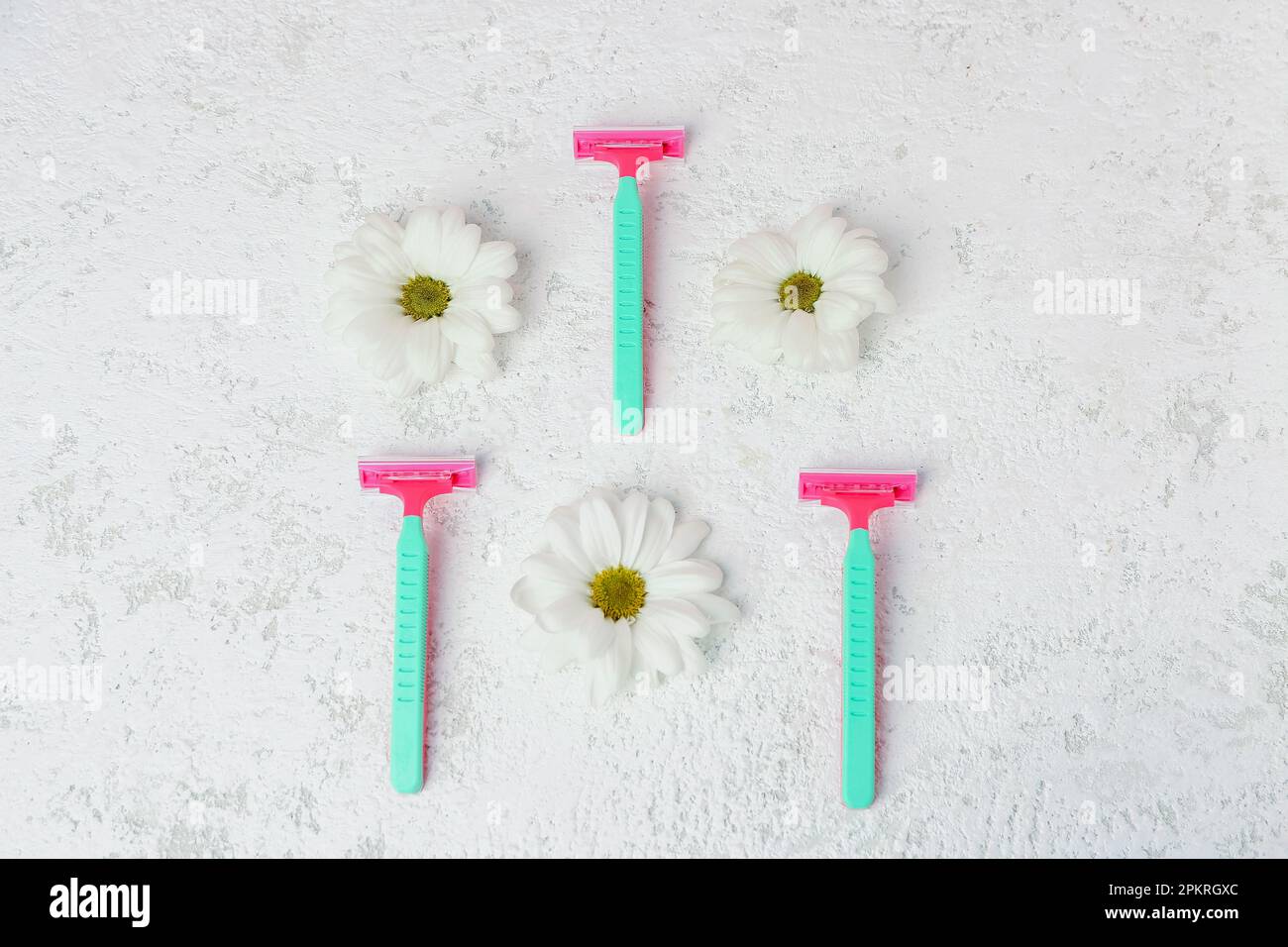 Composition with safety razors and daisy flowers on white grunge ...