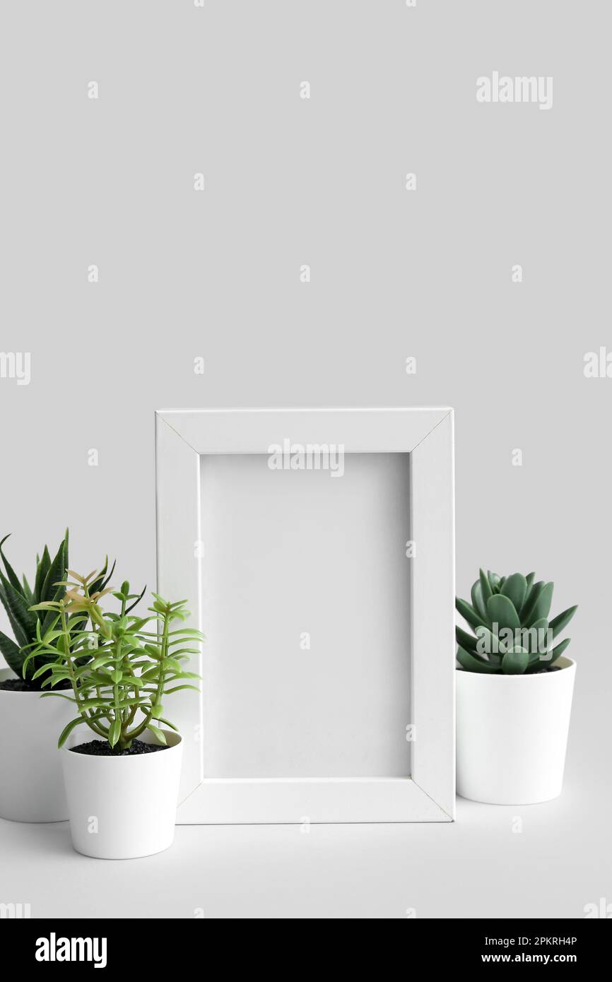 Artificial plants with blank frame on light background Stock Photo - Alamy