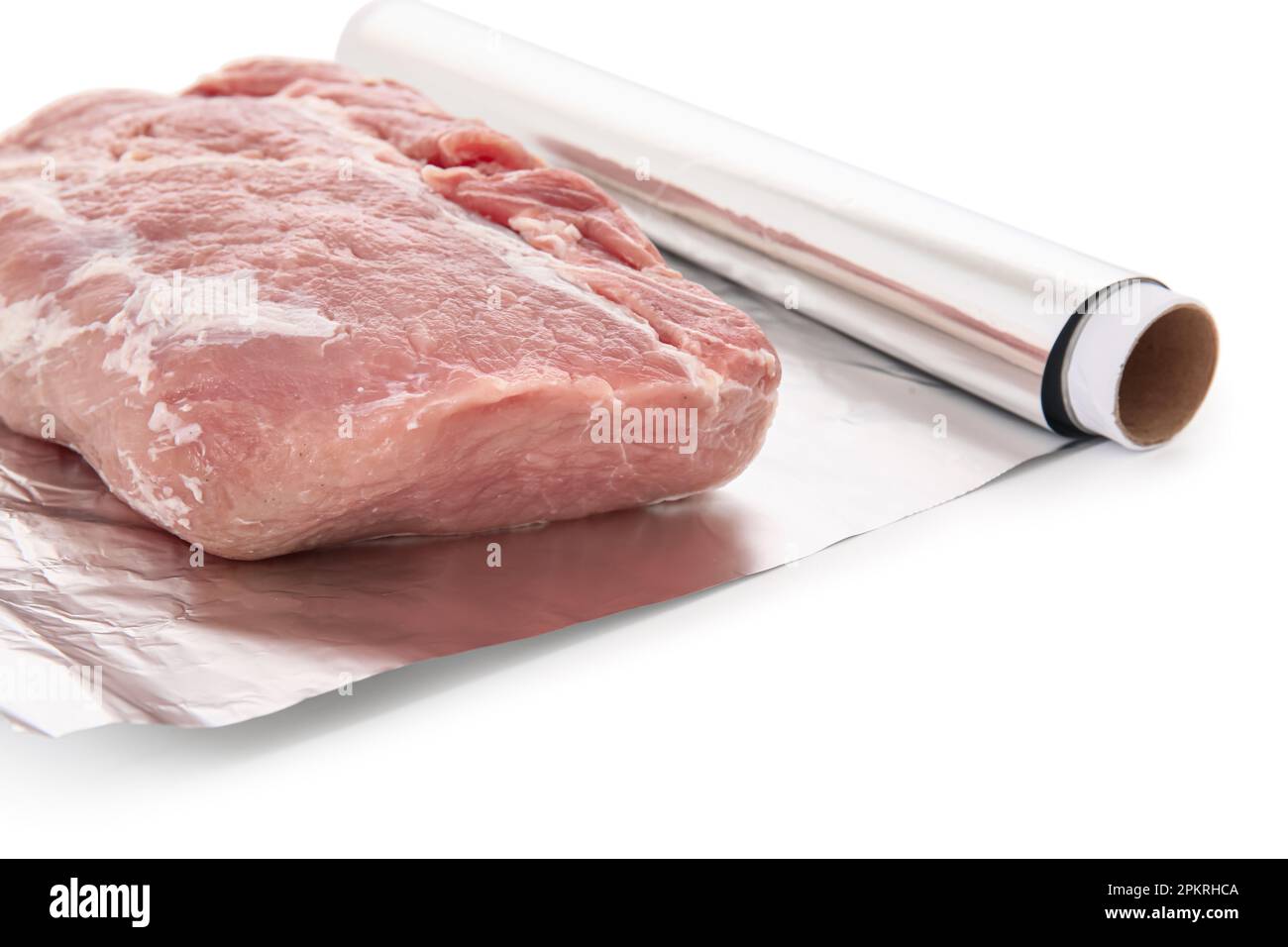 Aluminium foil roll with piece of raw meat on white background, closeup ...