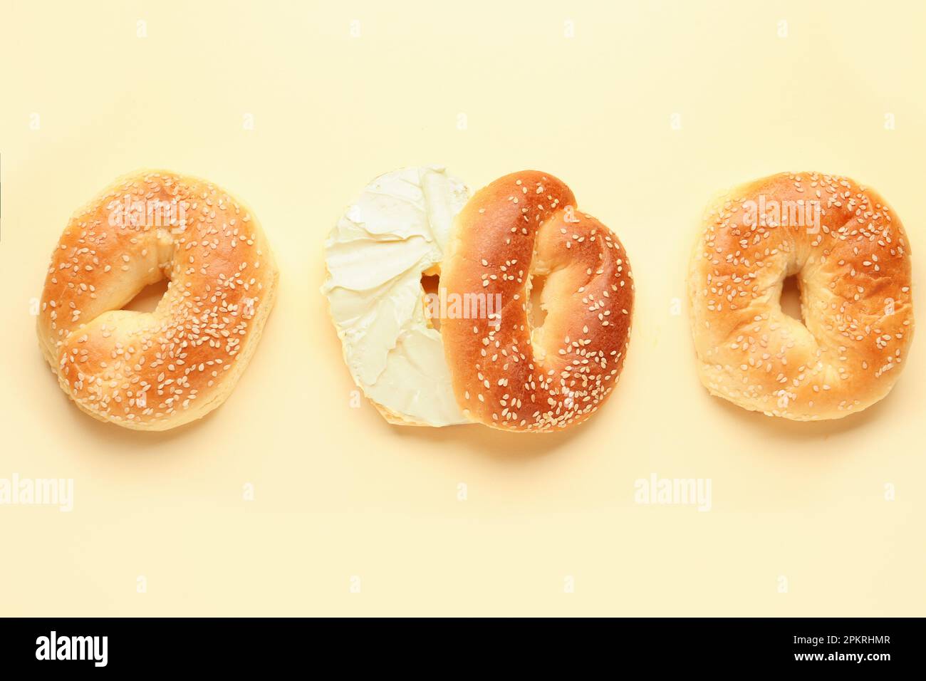Tasty bagels with sesame and cream cheese on beige background Stock ...