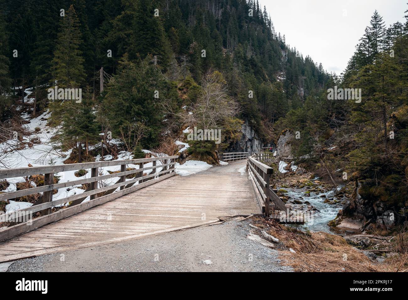 Beautiful mountain valley in early spring. Melt. A wooden bridge with ...