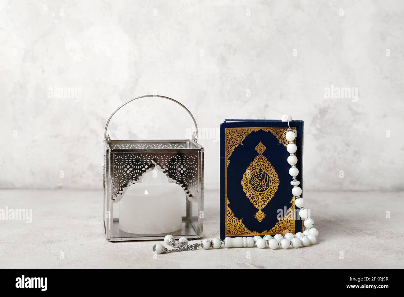 Muslim lamp with burning candle, Koran and prayer beads on grunge ...