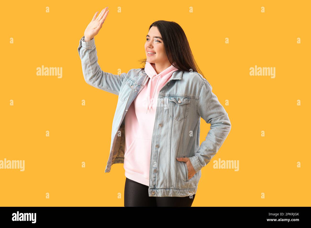 Beautiful young woman waving hand on yellow background Stock Photo - Alamy
