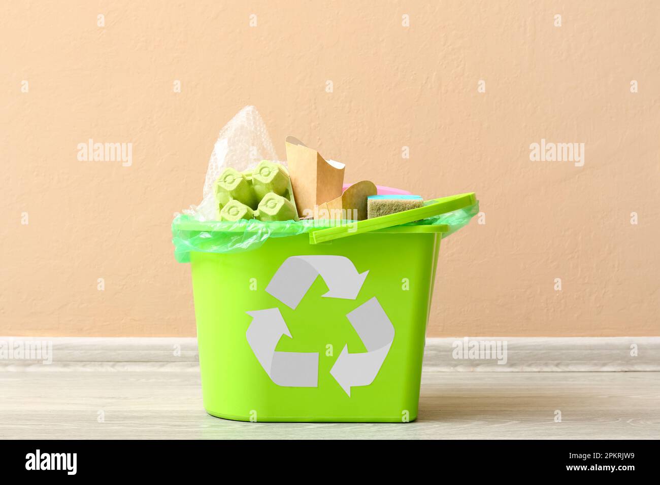 Recycling bin with garbage near beige wall Stock Photo - Alamy