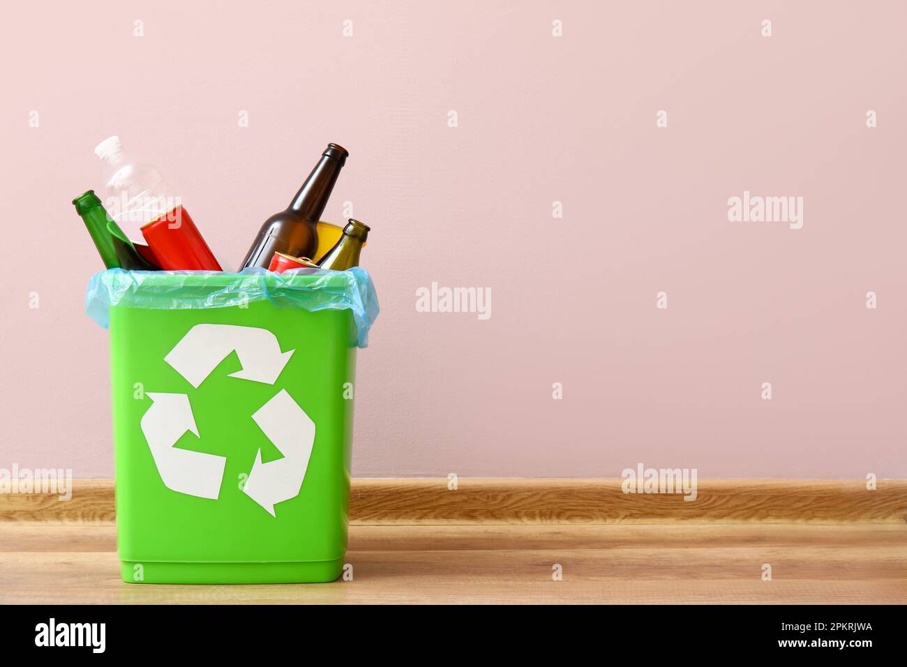 Recycling bin with bottles near pink wall Stock Photo - Alamy