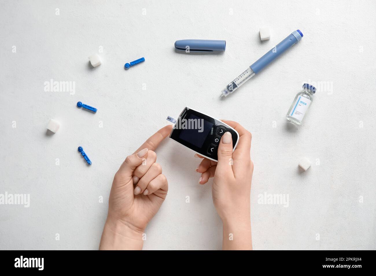 Diabetic woman with digital glucometer and insulin on white background ...
