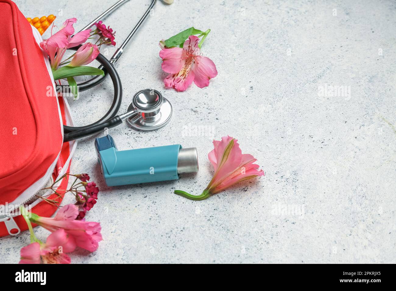 First aid kit with asthma inhaler, stethoscope and flowers on grunge ...
