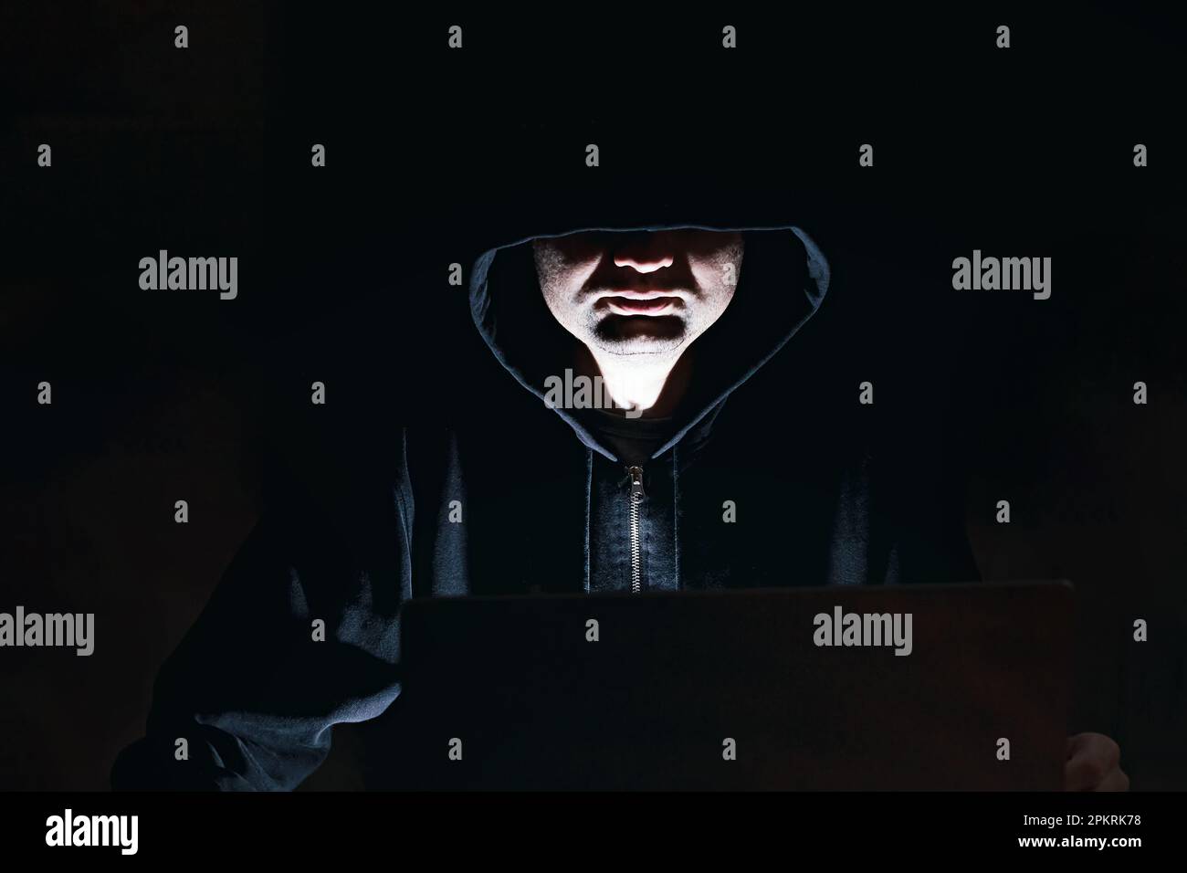 Man in the hoodie sitting in front of the laptop at night. Hacker ...