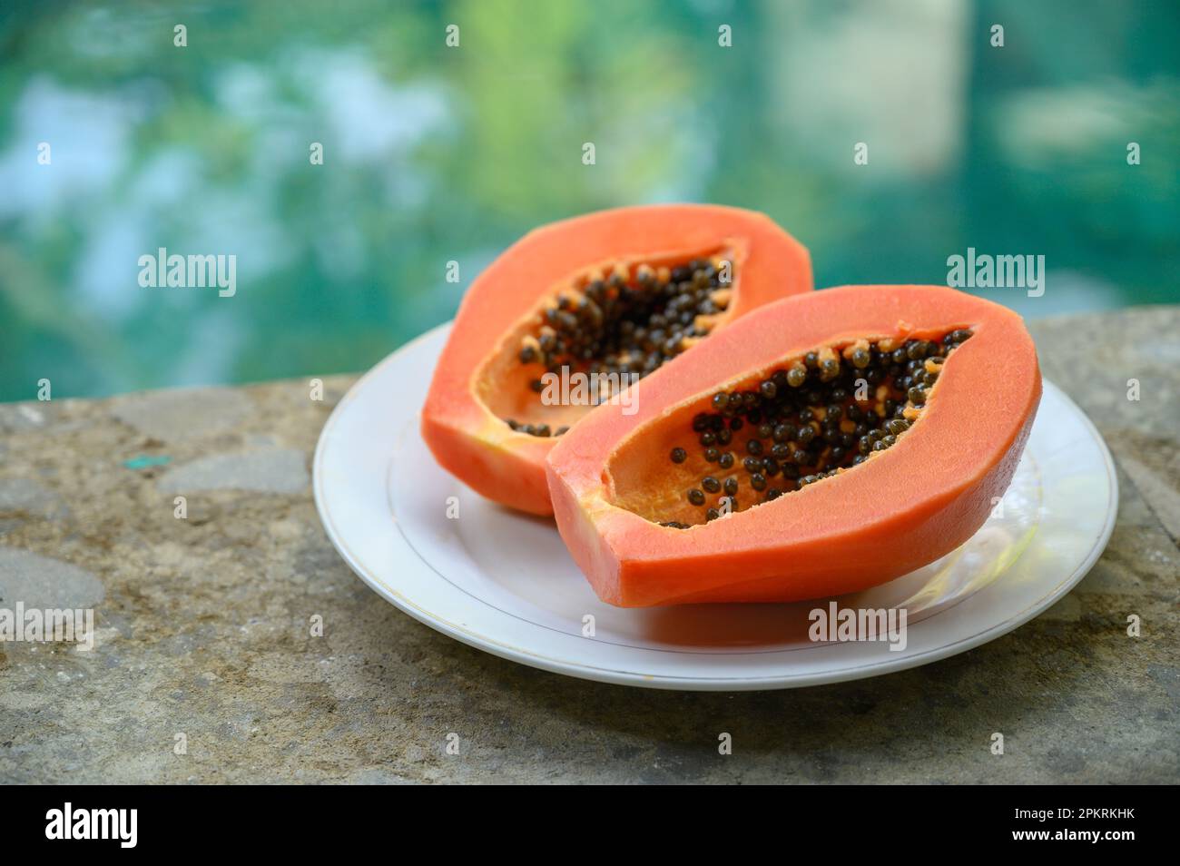 Two halves of peeled papaya in plate near swimming pool Stock Photo - Alamy