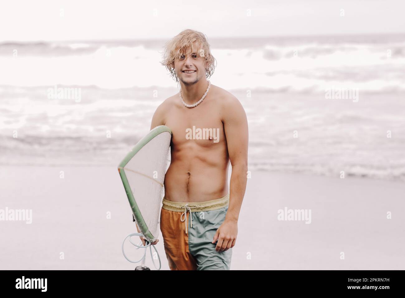 Handsome fit young blond man with mock up surfboard waits for wave to ...