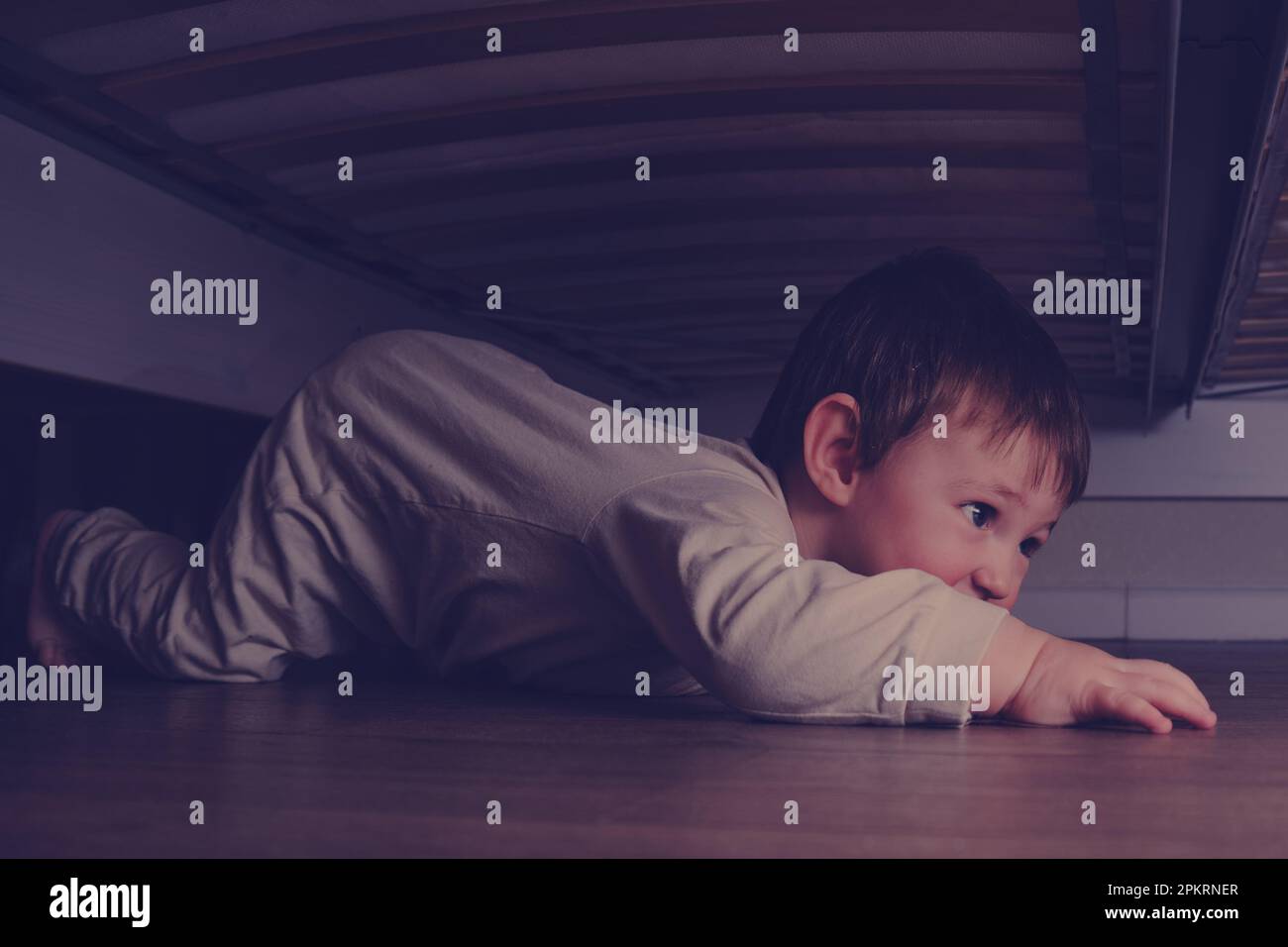 Toddler baby crawls and hides under the bed. Child climbed under the ...