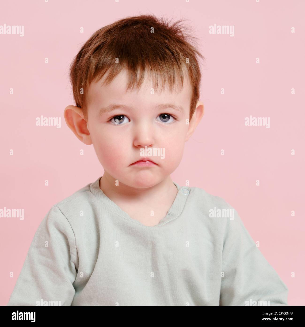 Sad toddler baby on studio pink background, copy space. Unhappy child ...