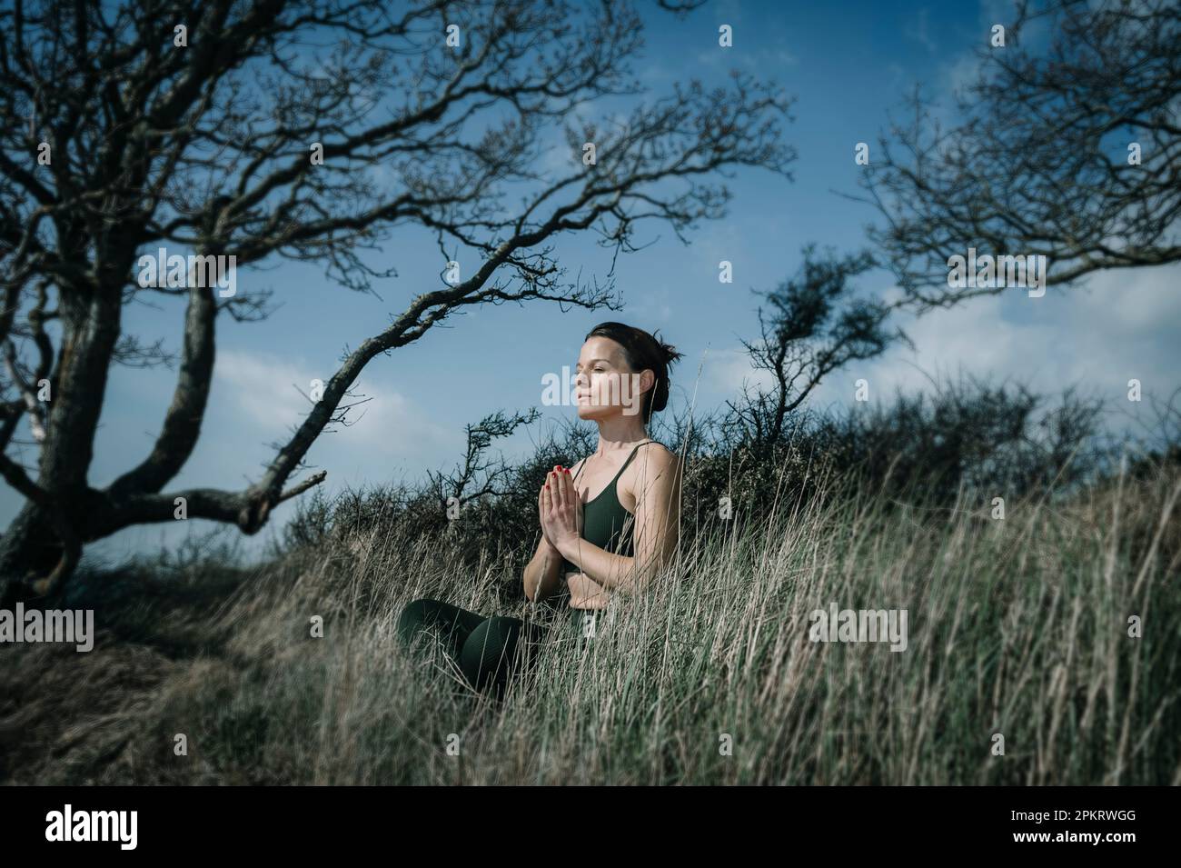 mid adult woman sitting meditating and practicing yoga outside in the ...