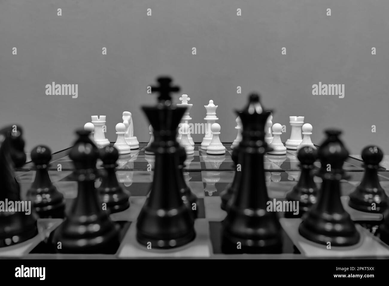 Black chess blurred pieces against background white chess pieces ...